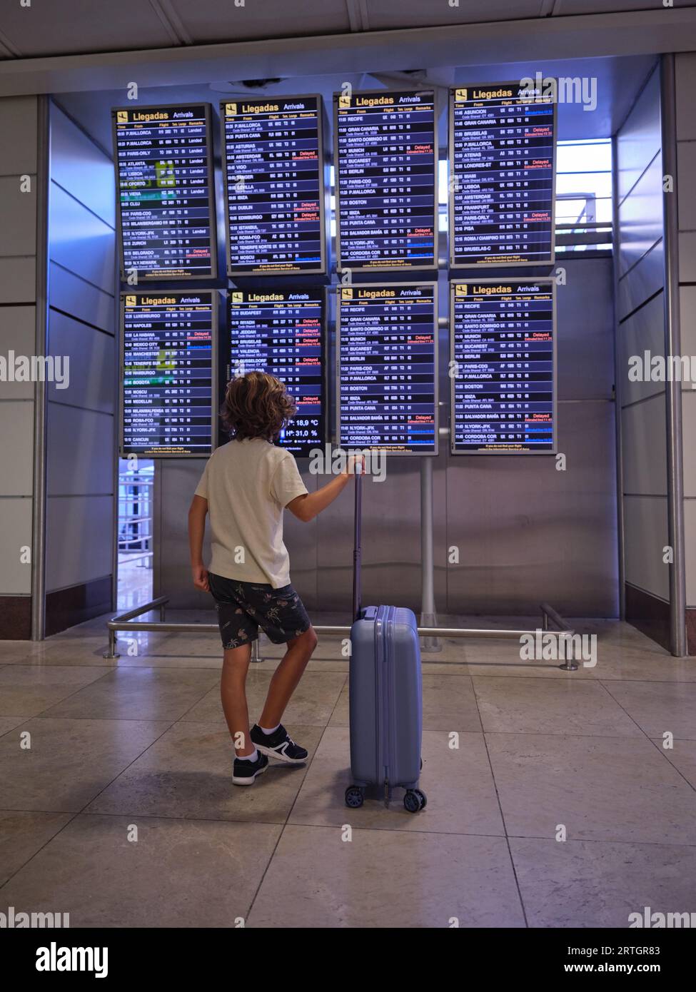 Back view of faceless child in casual clothes with blue suitcase ...