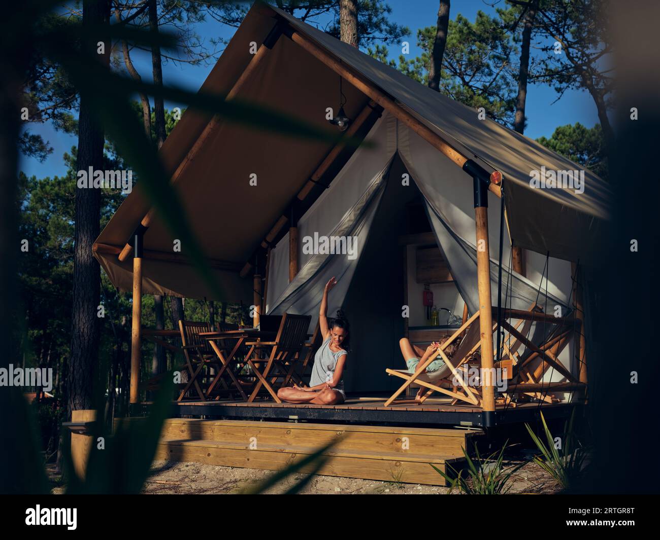 Distant mother stretching in lotus pose while sitting near son on ...