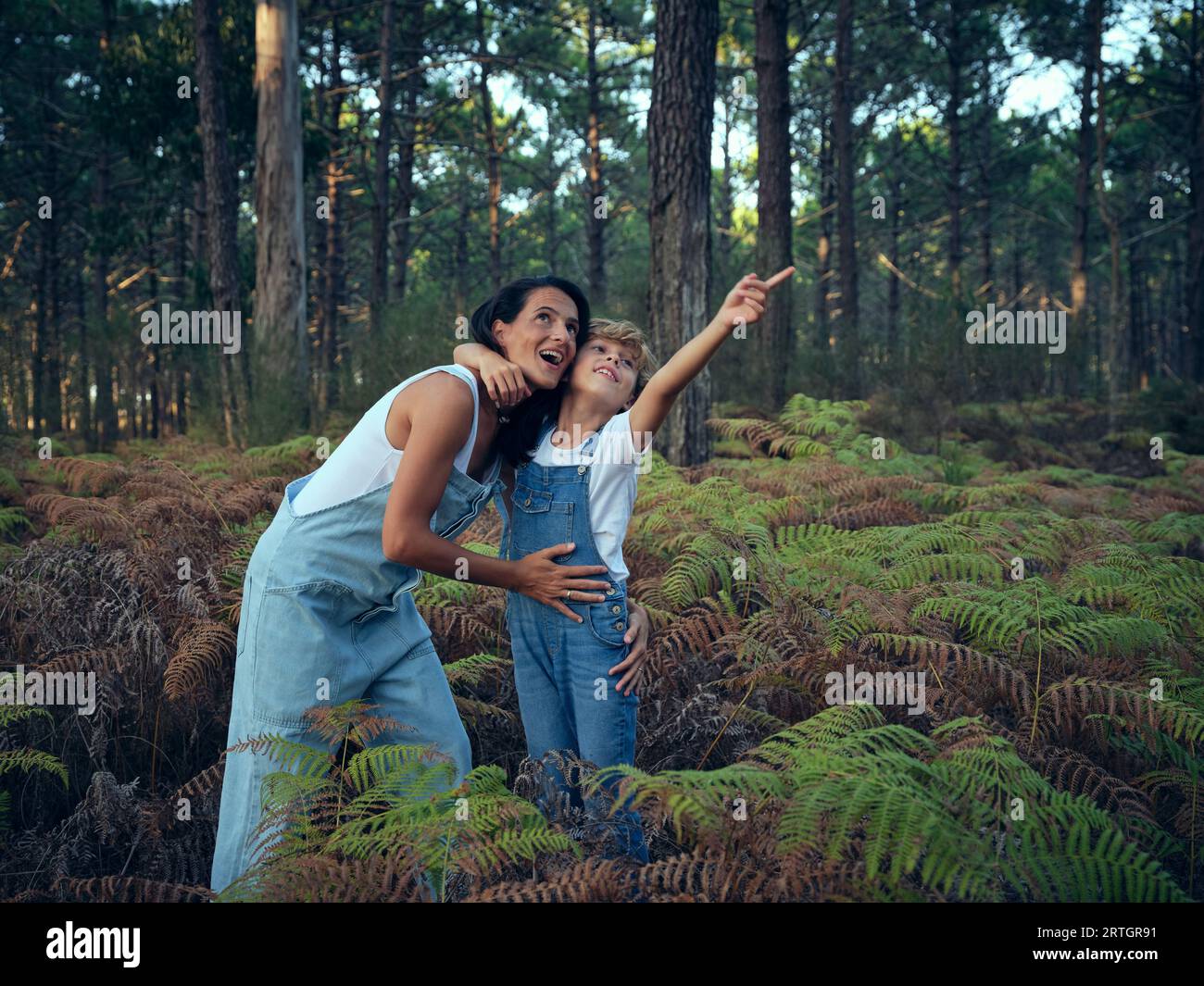 Woman with mouth opened and smiling boy pointing away in matching ...
