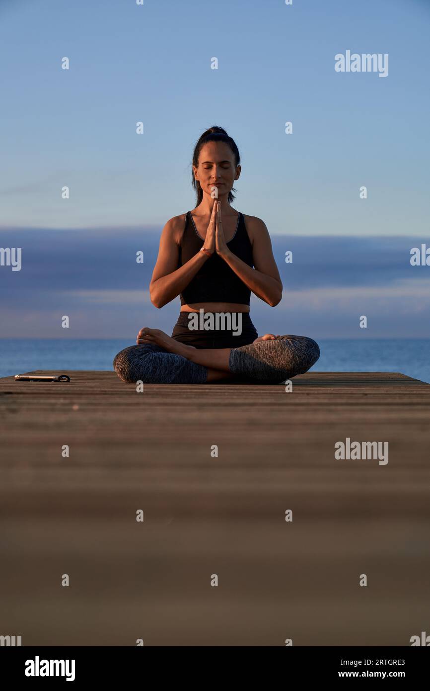 Full body of calm Hispanic female with closed eyes practicing lotus ...