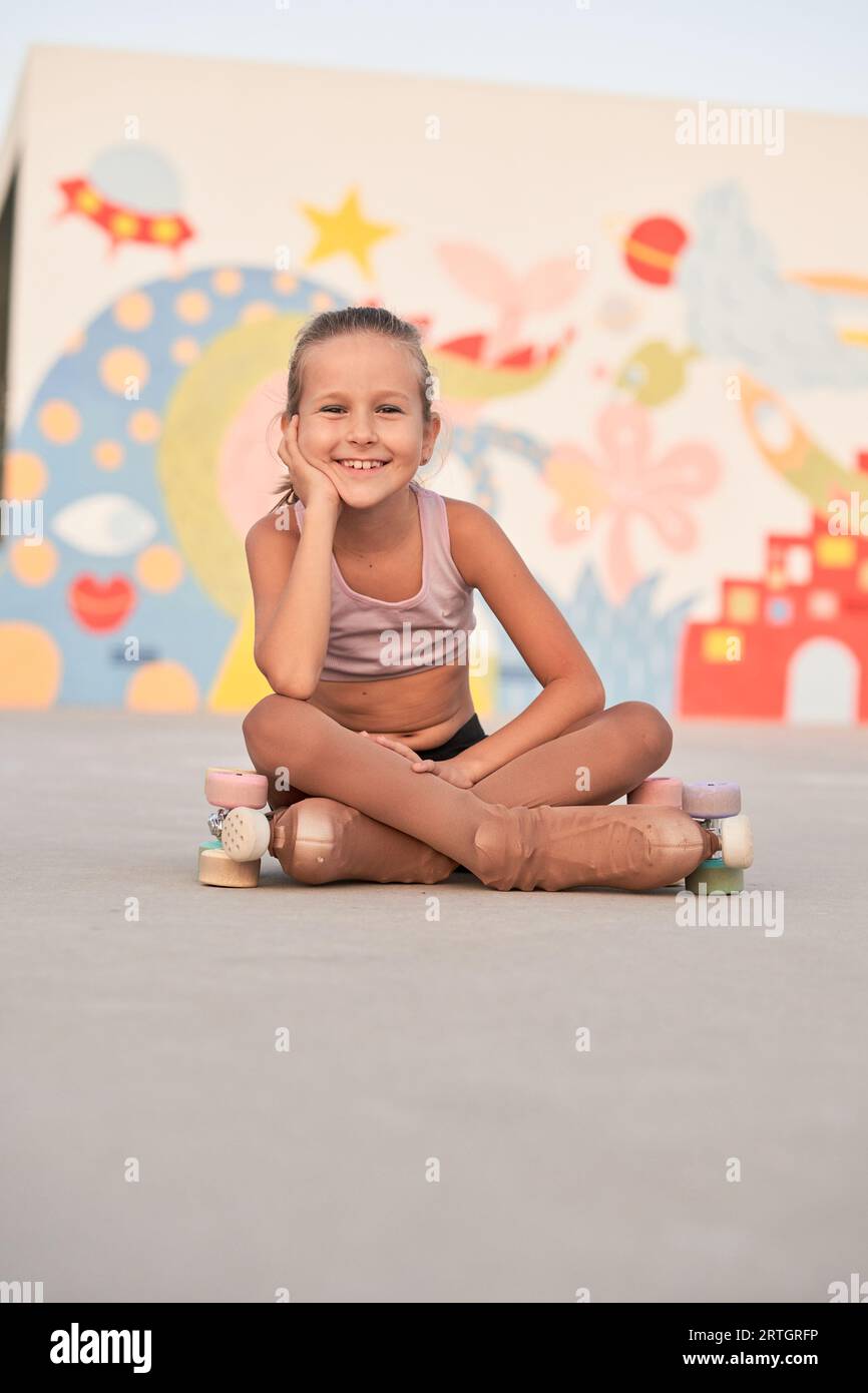 Portrait of smiling preteen girl in activewear and quad roller skates ...