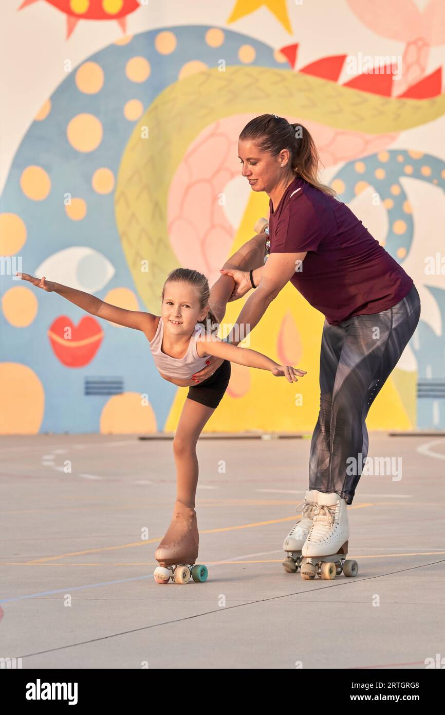 Happy blondie girl doing roller skate exercises with raised in side ...