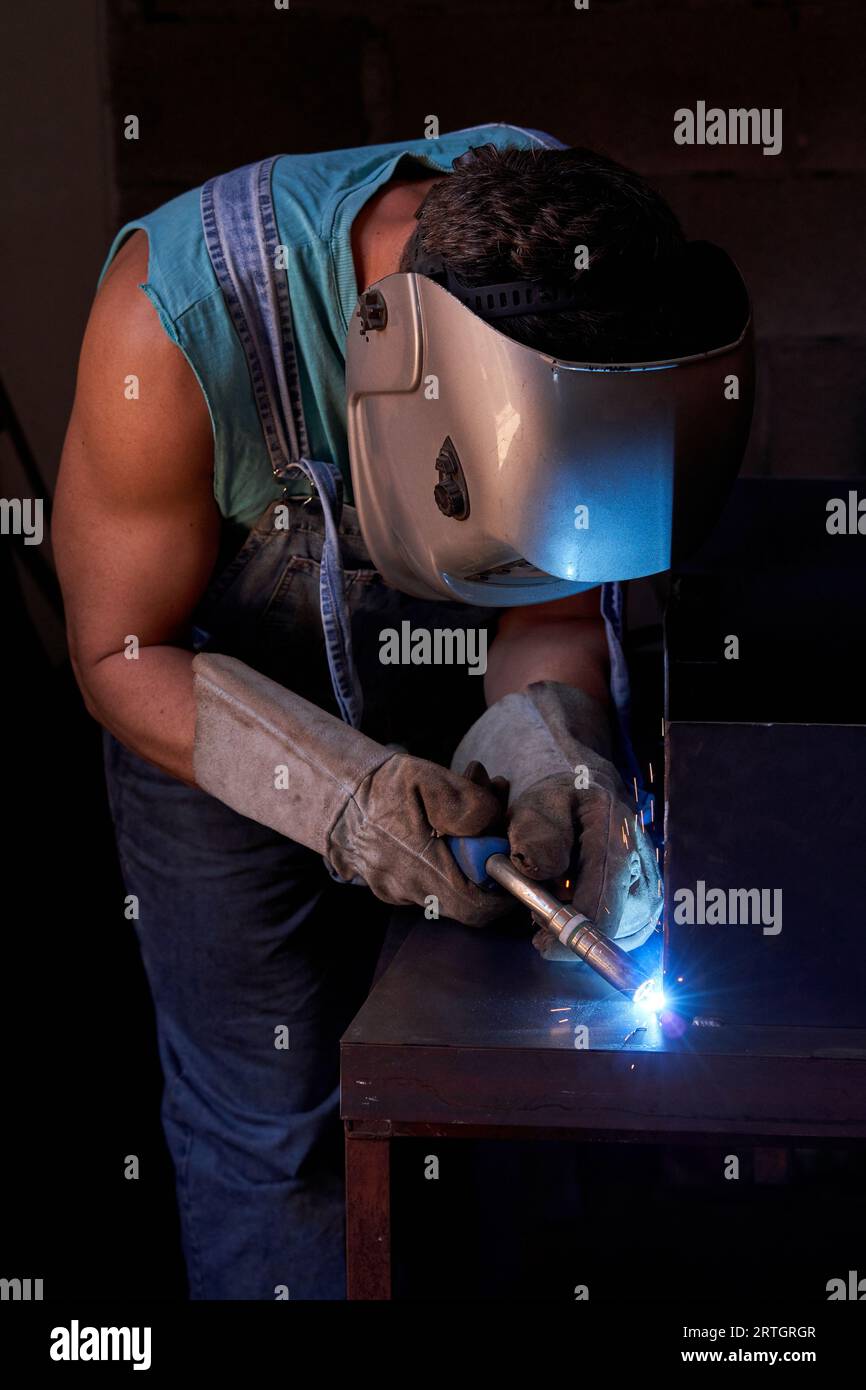 Faceless male in protective mask using welding machine to weld metal ...