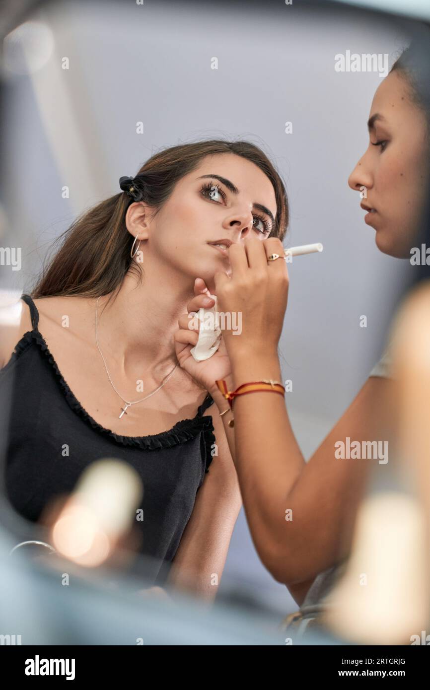 Professional female visagiste applying lipstick on lips of attractive ...