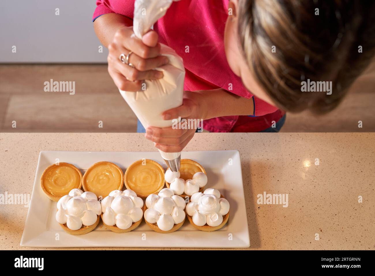 Top view of crop anonymous female pastry chef making peaks of cream on ...
