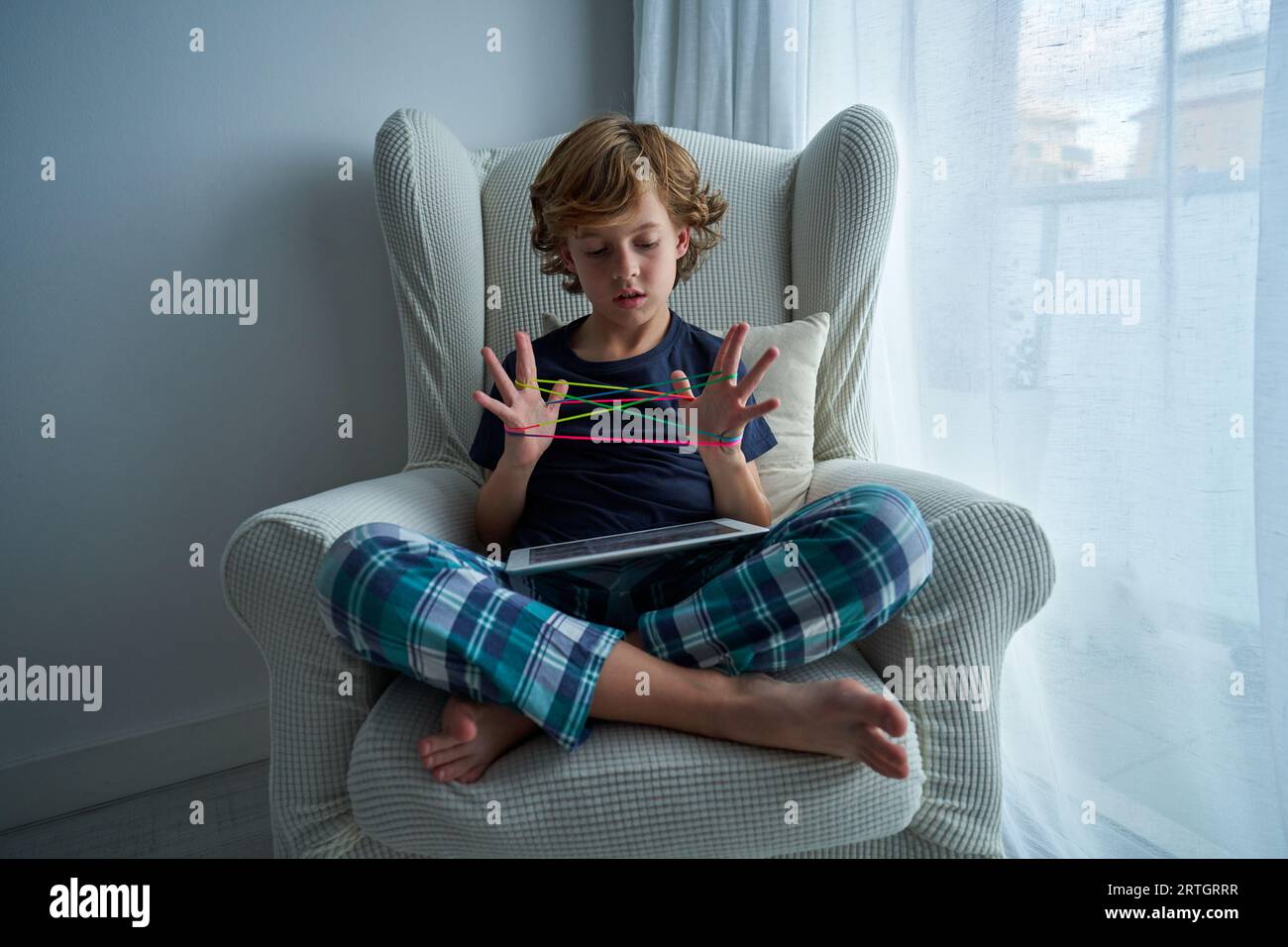 Full body of barefoot focused boy watching video on modern tablet while ...