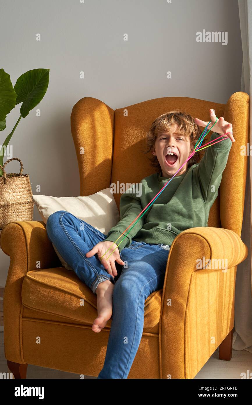 Portrait of laughing child in casual clothes sitting in armchair and ...