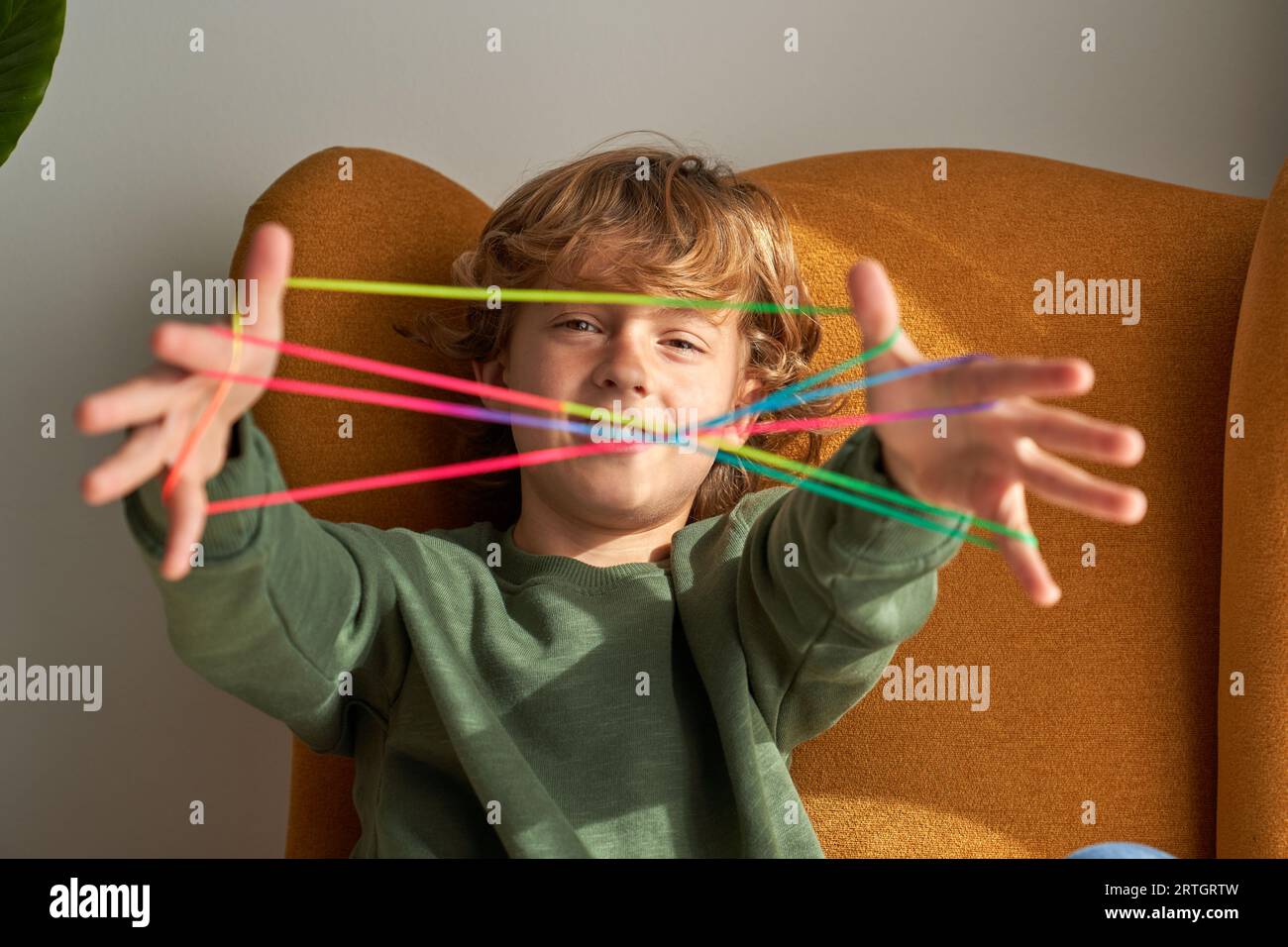 Satisfied preteen kid sitting in armchair and looking at camera while ...