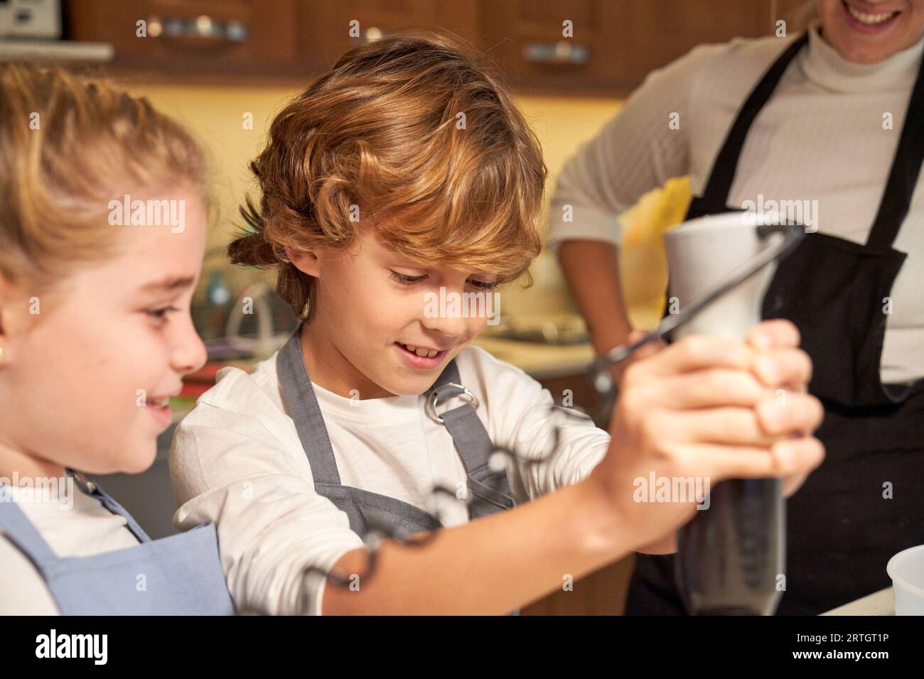 Positive siblings blending food in electric blender with wire while ...