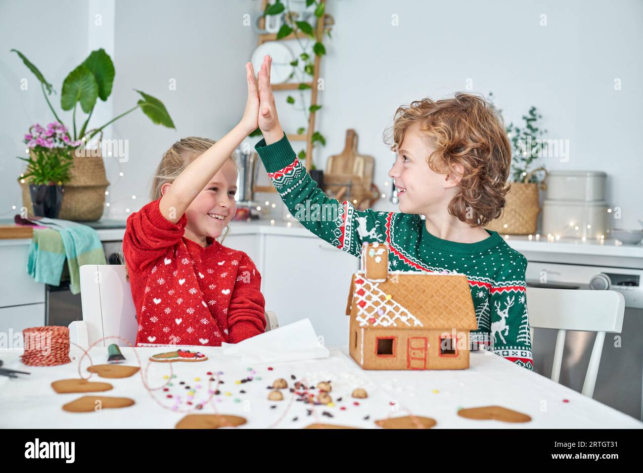 Positive children giving high five to each other while sitting near ...