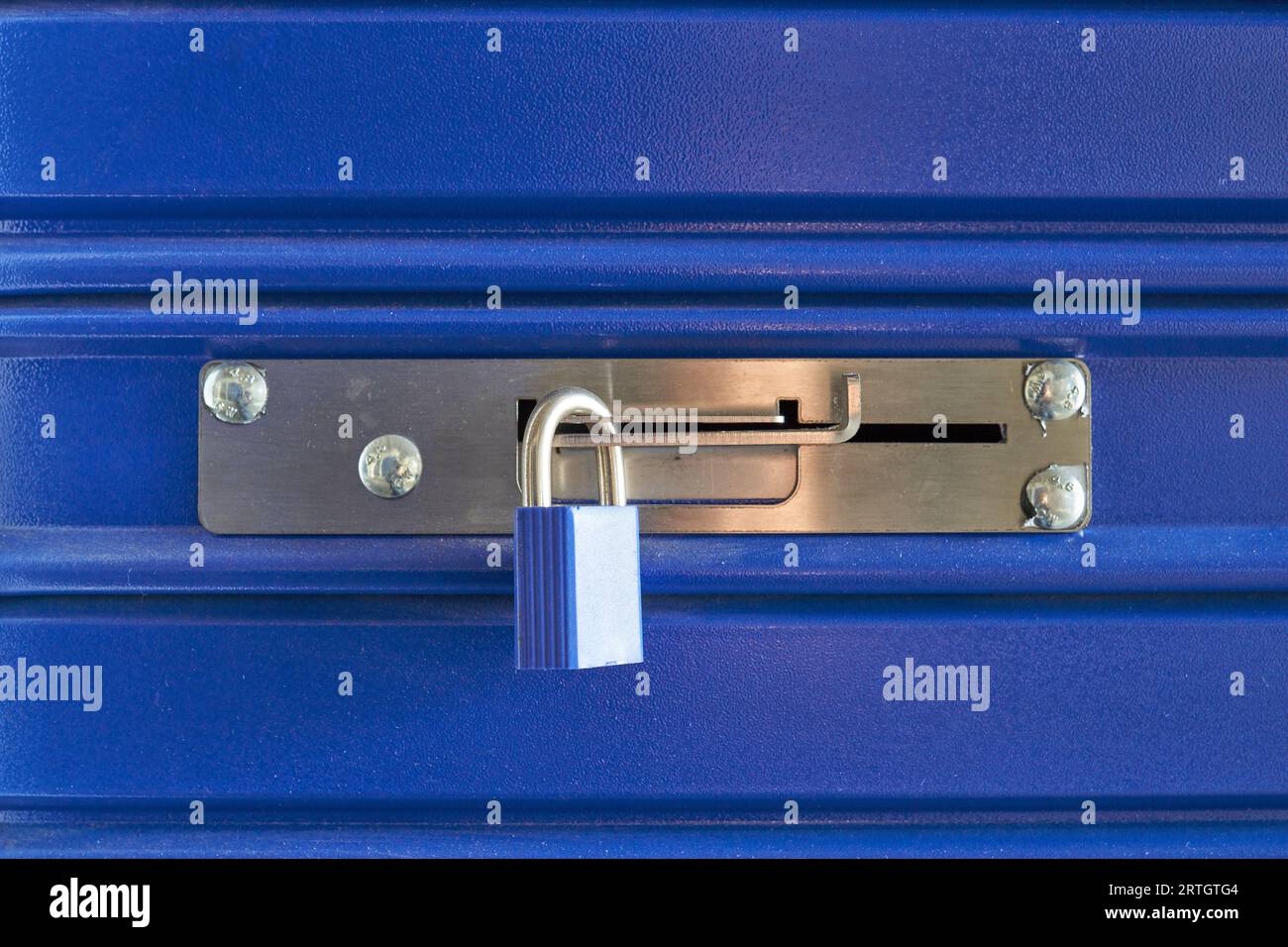 A blue locked lock on a metal barrier in a storeroom Stock Photo - Alamy