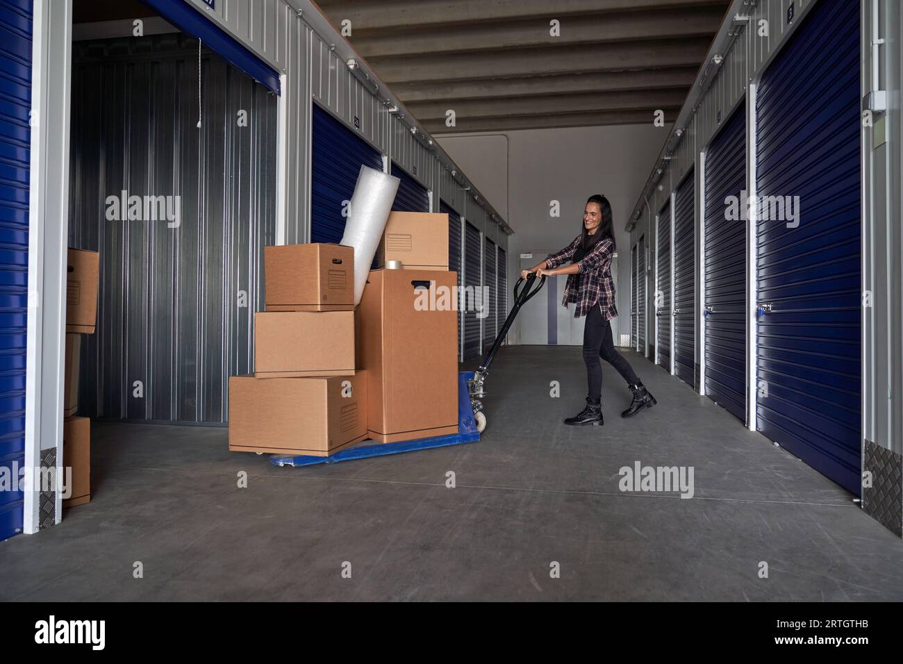 Full body side view of optimistic female using special manual pallet ...