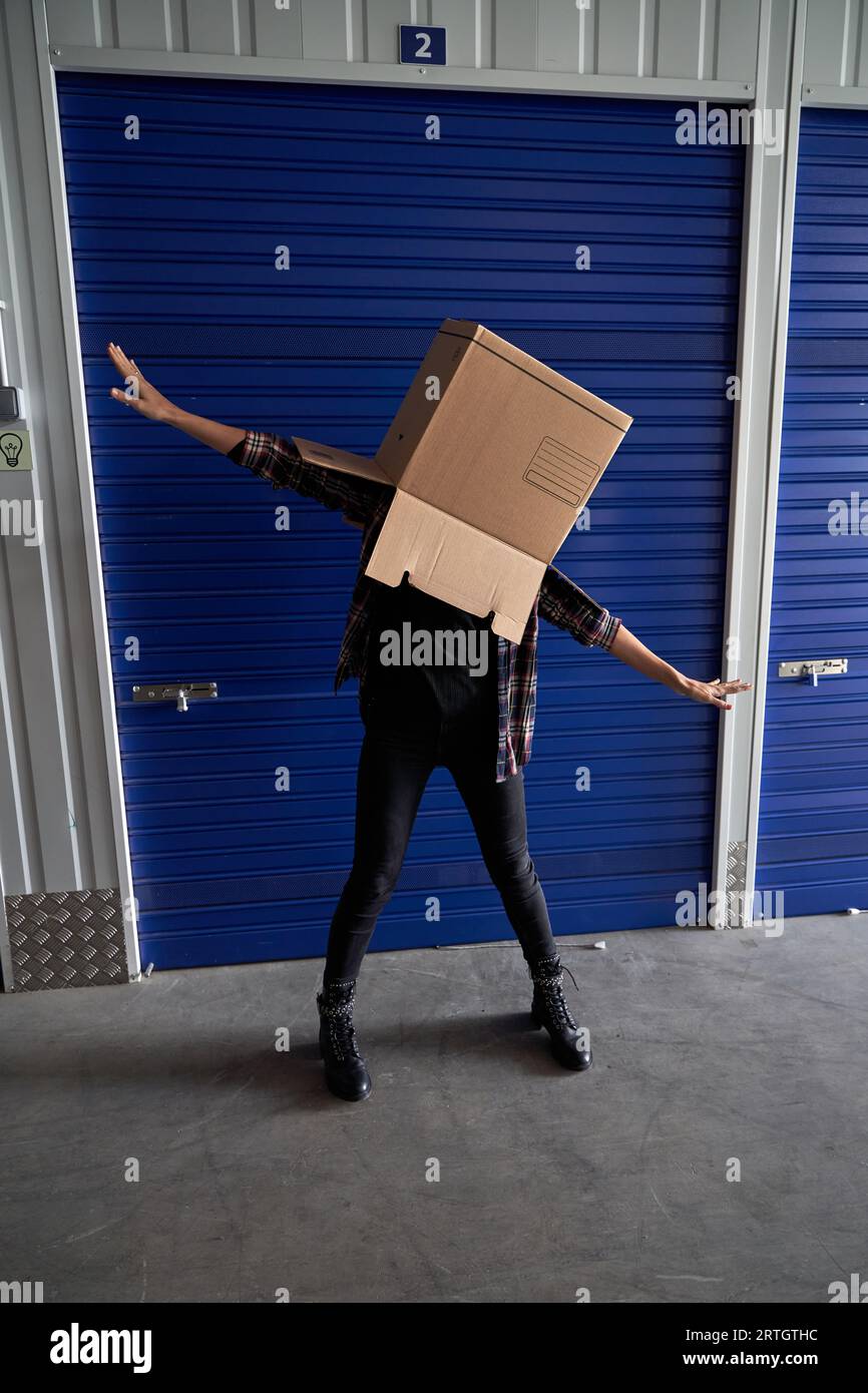 Full body of unrecognizable person with carton box on head standing ...