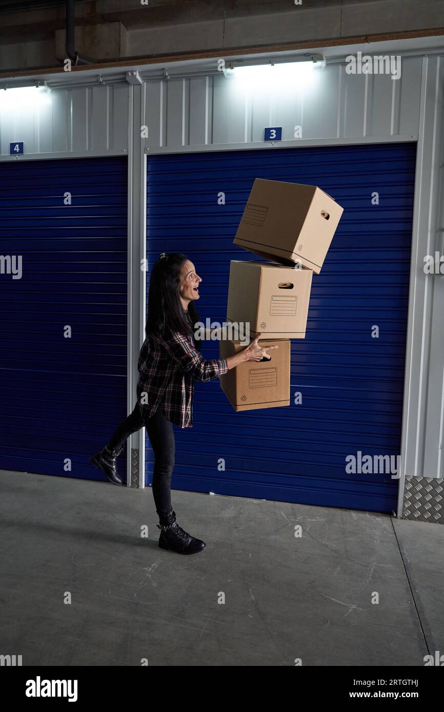 Full body side view of shocked female carrying falling packing boxes ...