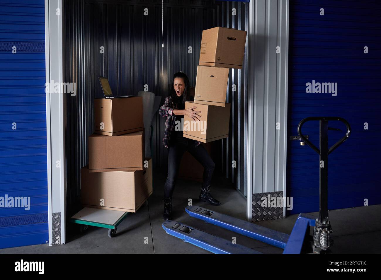 Full body of female with closed eyes carrying heavy carton boxes with ...