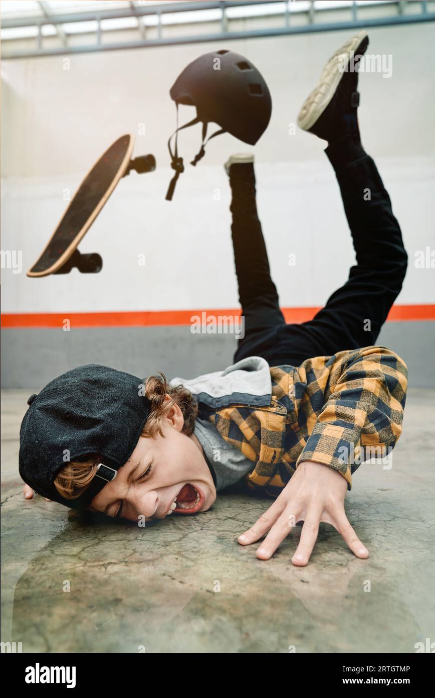 Displeased little child crying while falling from skateboard on street ...