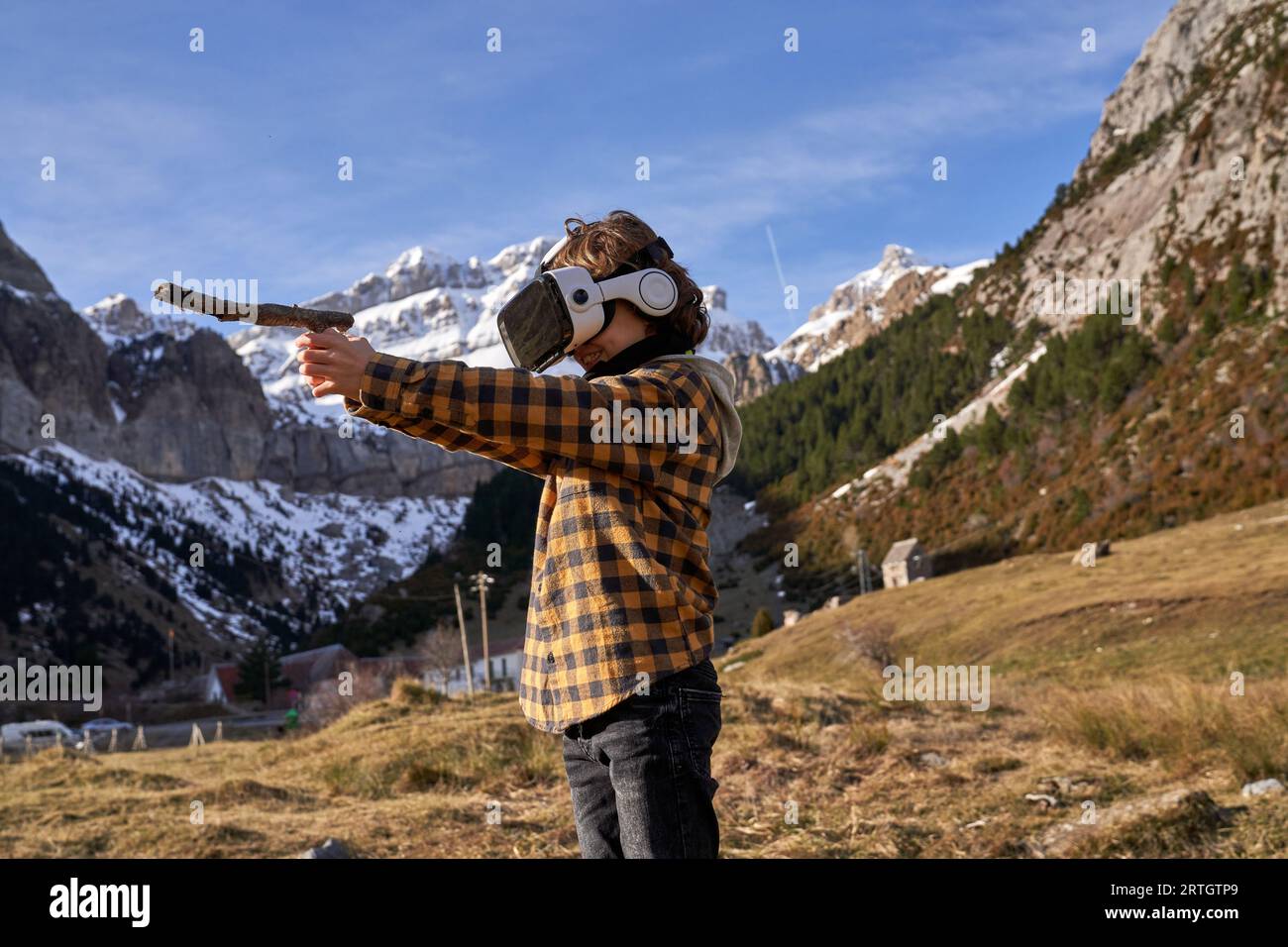 Side view of boy in virtual reality headset and tree branch as ...