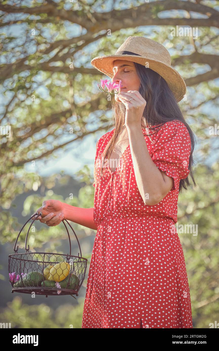 Side view of tranquil female smelling vivid flower under trees on ...