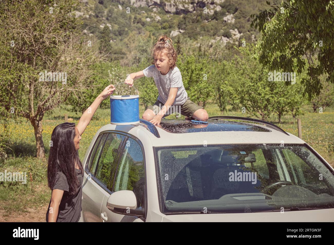 Side view of female in casual clothes picking up bucket with from son ...