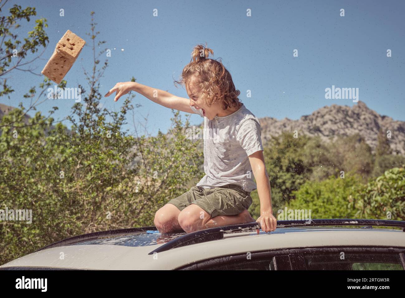 Side view full length of little kid throwing sponge in sunny summer day ...