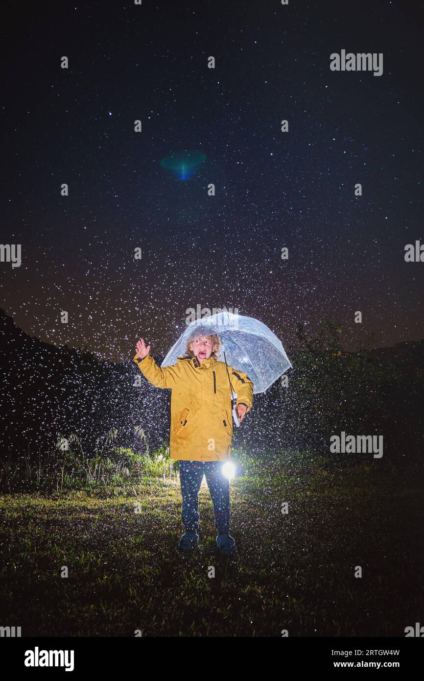 Full body of anonymous child in yellow outfit standing with umbrella ...