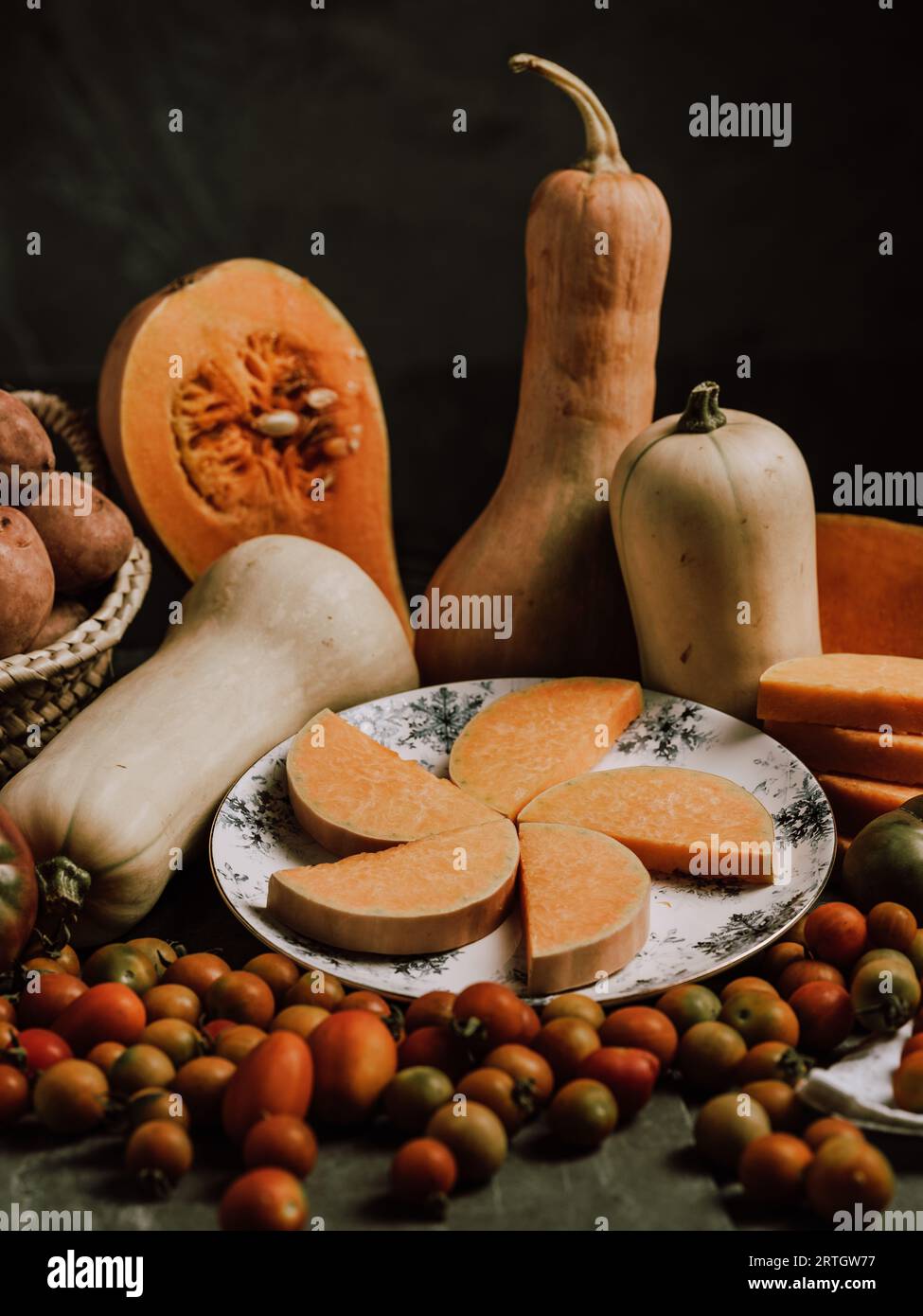 Still life of plate with slices of nutmeg pumpkin surrounded with green ...