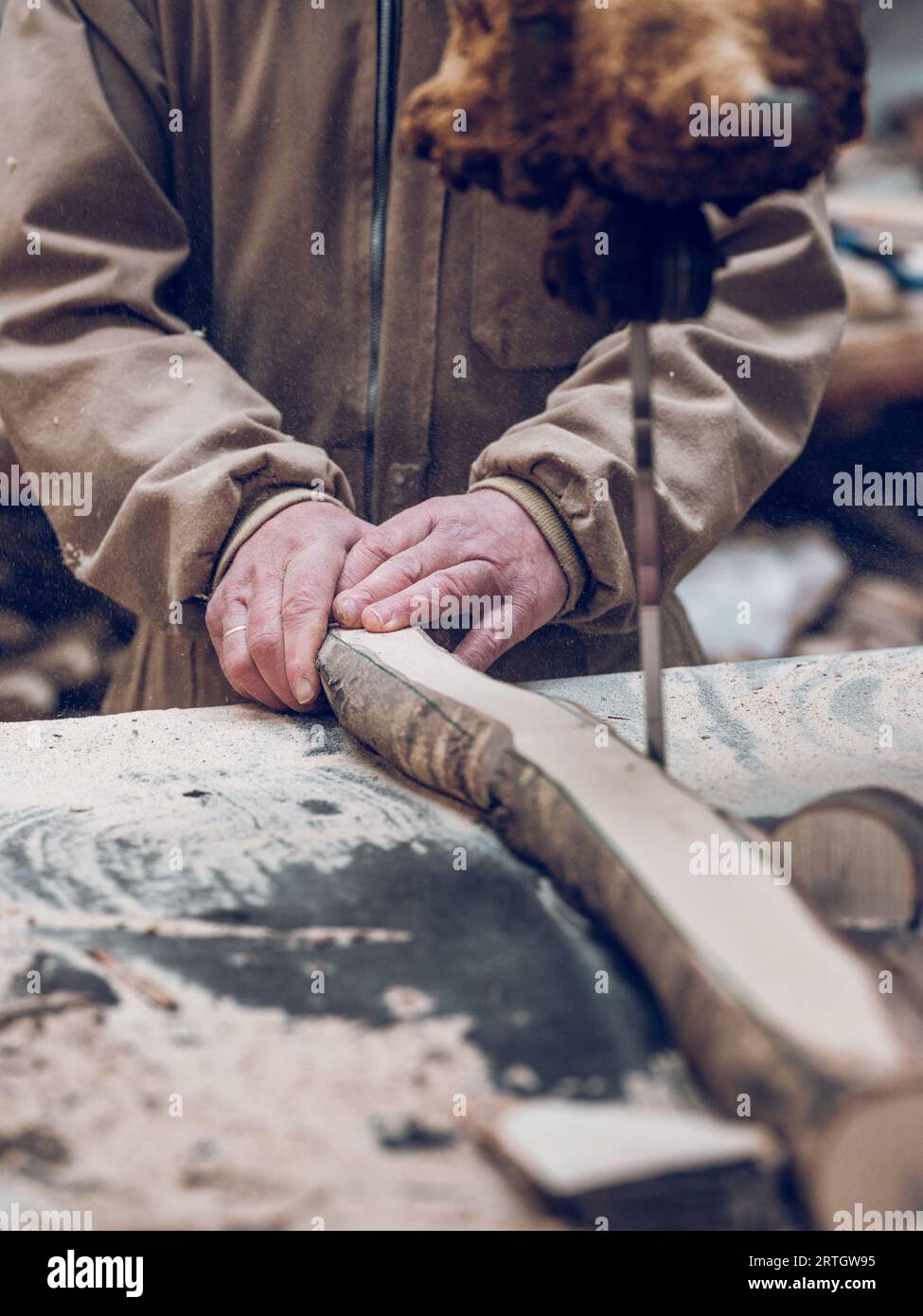Crop anonymous male woodworker cutting wooden detail with scroll saw ...
