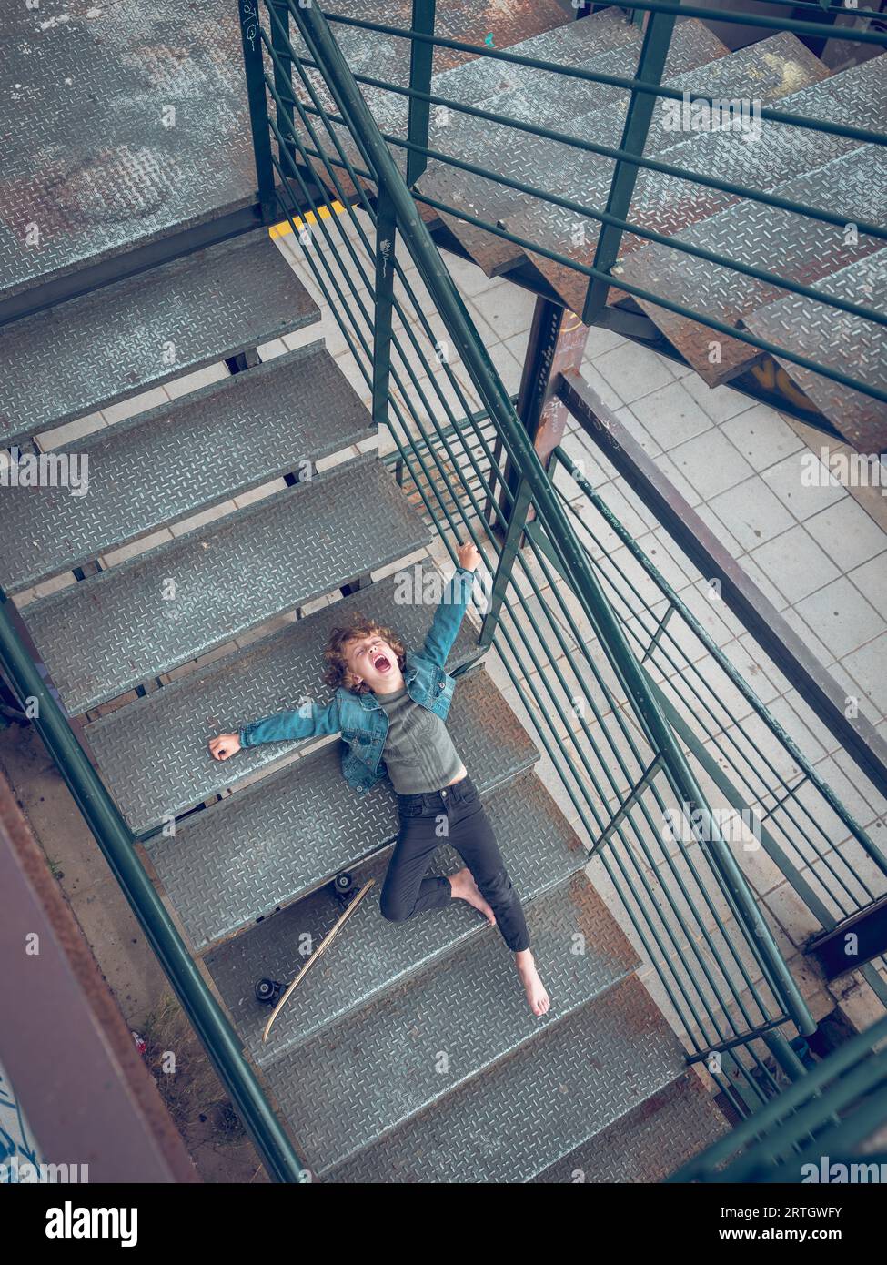 From above of full body preteen boy lying on steps of staircase with ...
