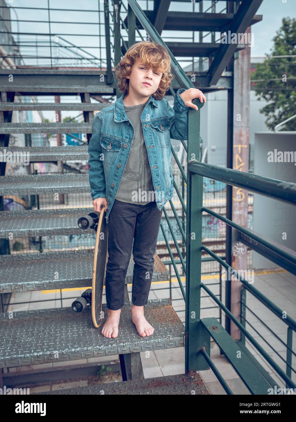 Full body of calm cute boy in casual clothes with penny board standing ...