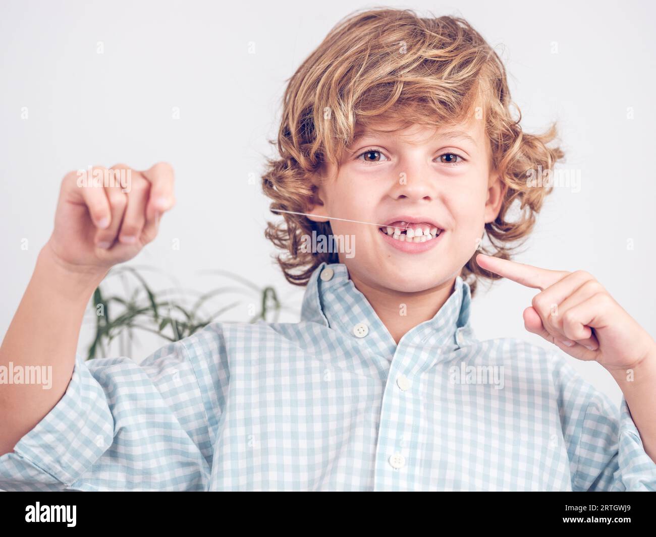 Cute courage preteen boy demonstrating twitched out tooth with thread ...