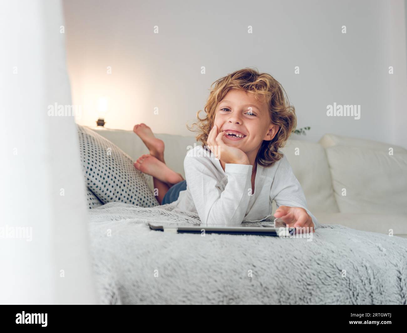 Full body of barefoot cheerful cute preteen boy lying on sofa with ...