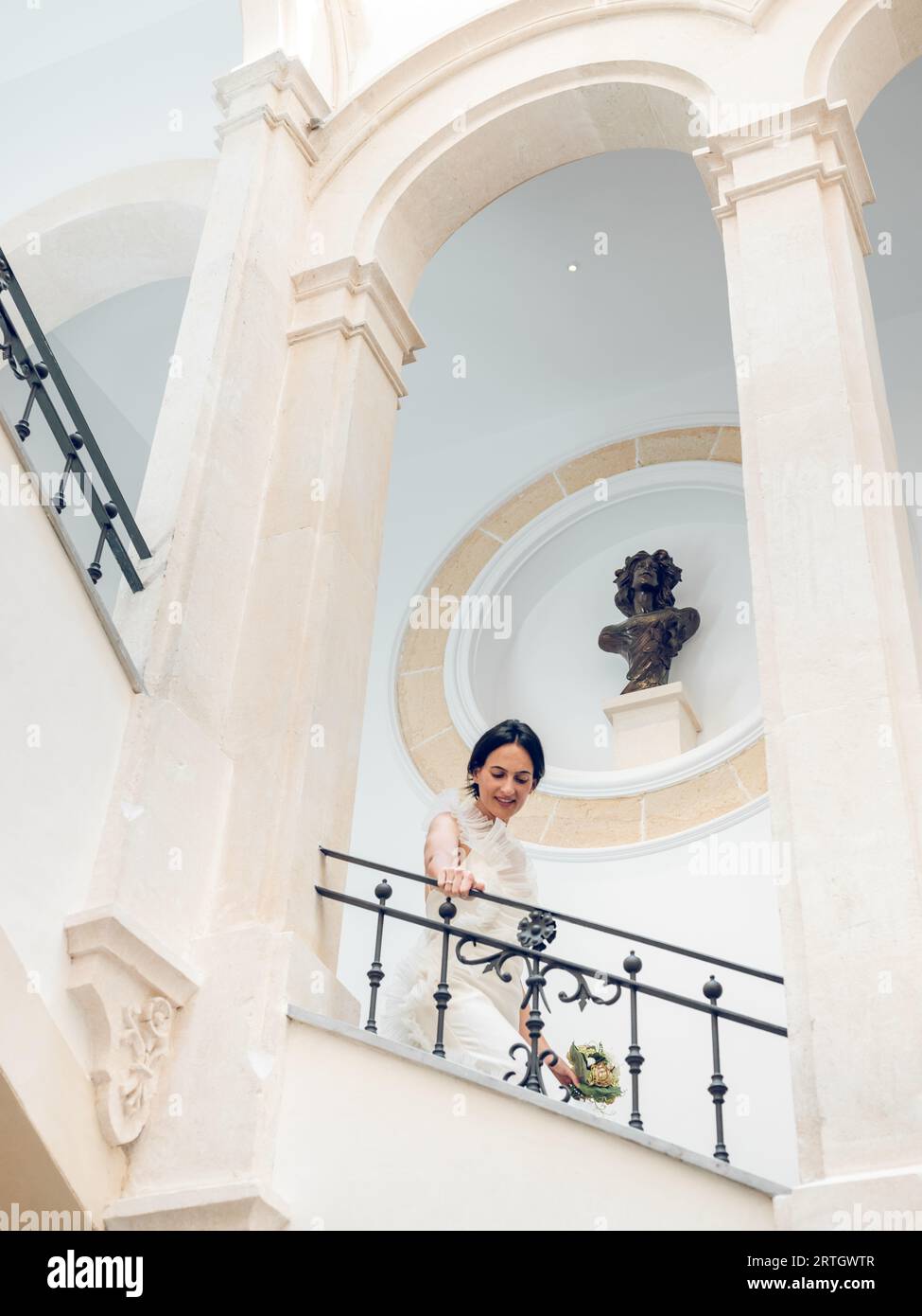 From below of young newlywed female walking downstairs on staircase in ...