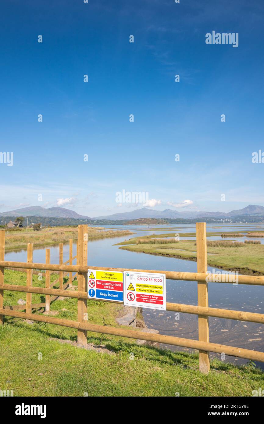 Warning sign and notice in English and Welsh attached to a wooden fence ...