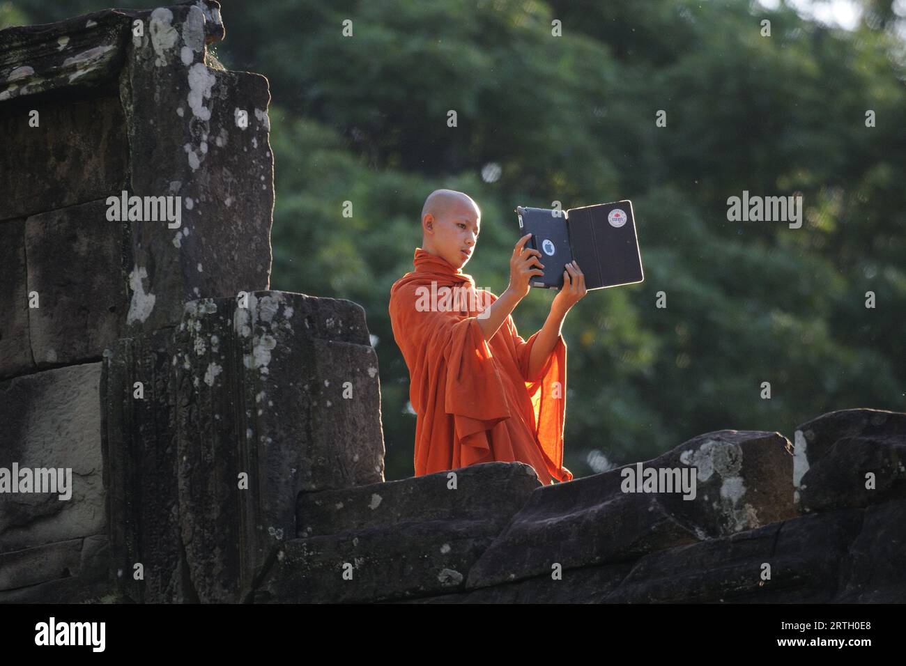 A young Monk looking into an iPad, Monk posing with iPad, Young Monk in Cambodia, Monk clicking ...