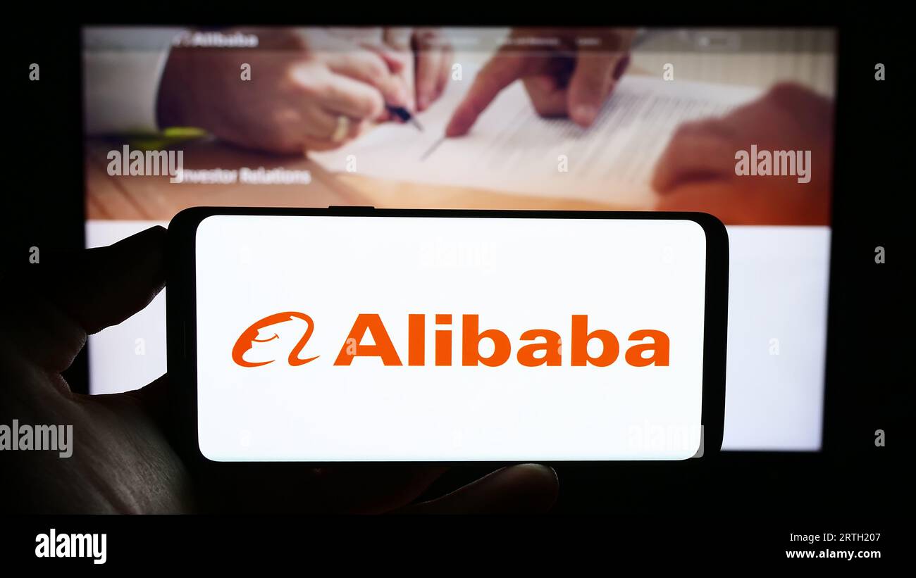 Person holding mobile phone with logo of Chinese company Alibaba Group ...