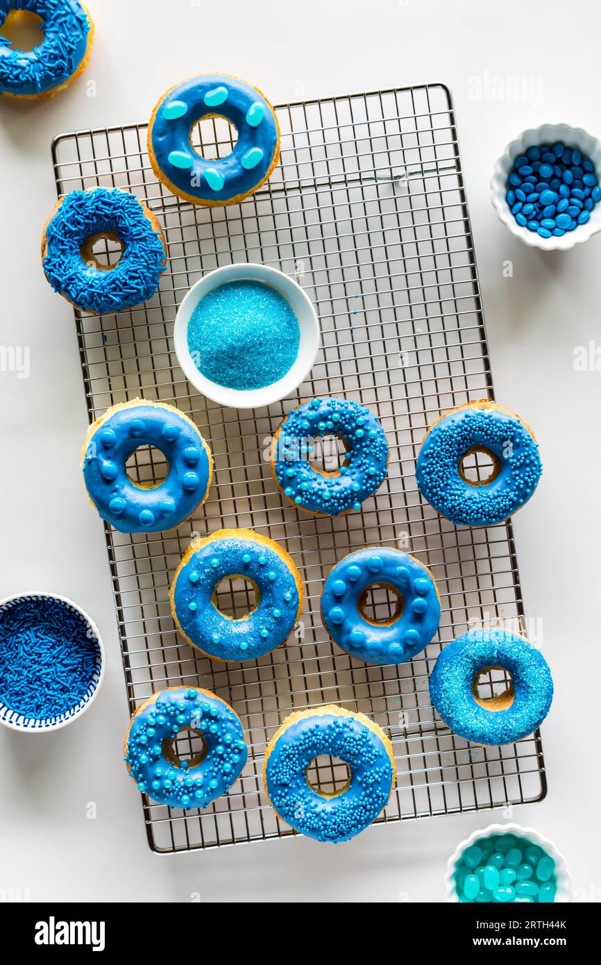 A cooling rack topped with homemade blue decorated donuts Stock Photo ...