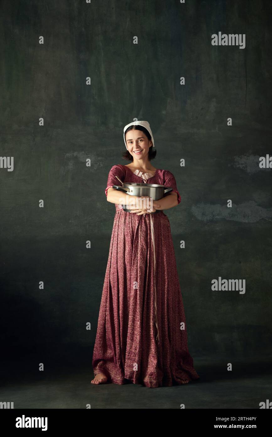 Portrait of happy young woman, medieval maid in long dress standing ...