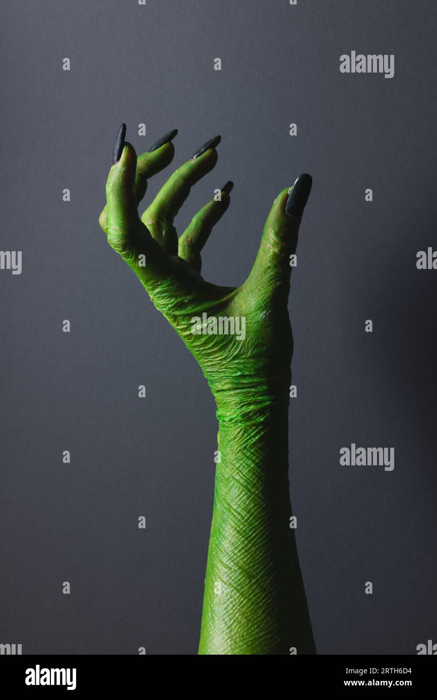 Vertical image of green monster hand with black nails with hold gesture ...