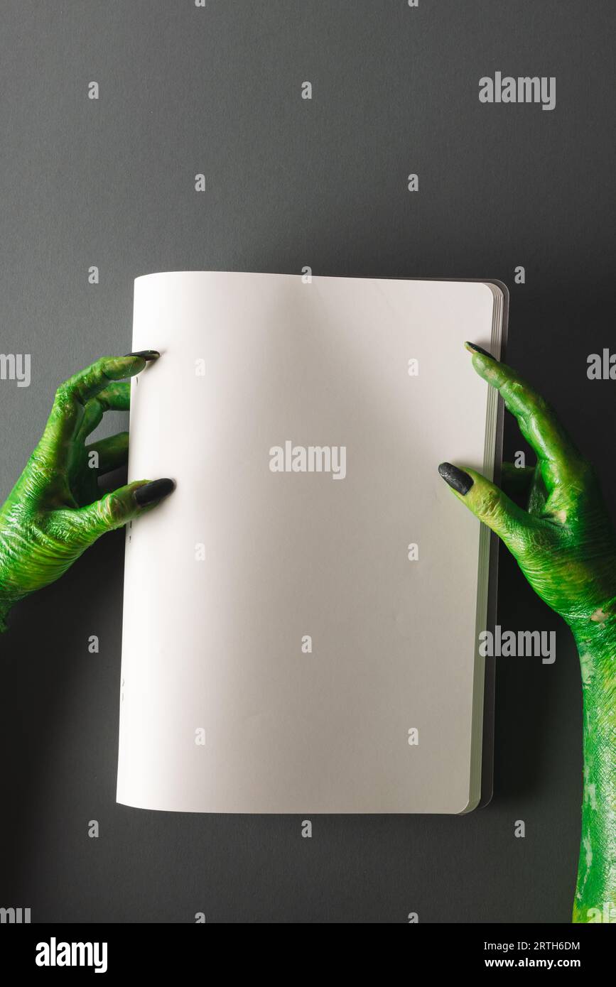 Vertical image of green monster hands holding notebook with copy space ...