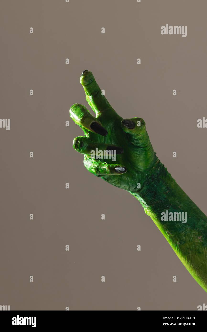 Vertical image of green monster hand with black nails making gesture on ...