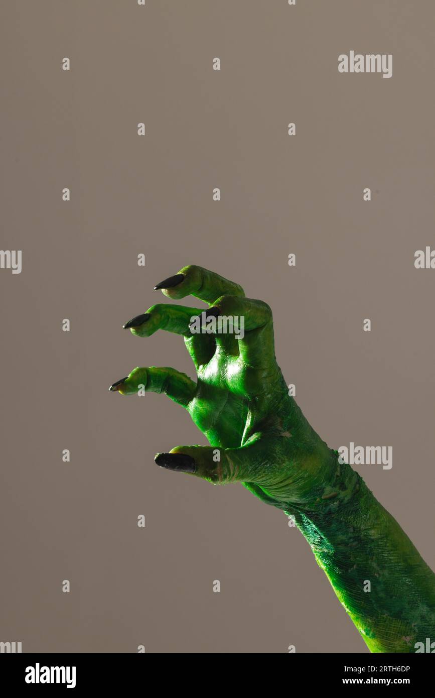 Vertical image of green monster hand with black nails making gesture on ...