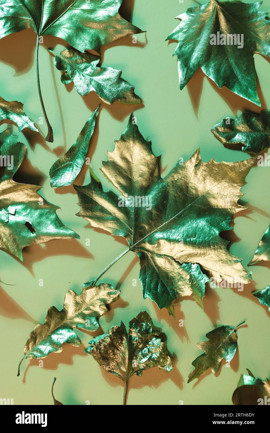 Vertical image of metallic gold autumn leaves lying on orange ...