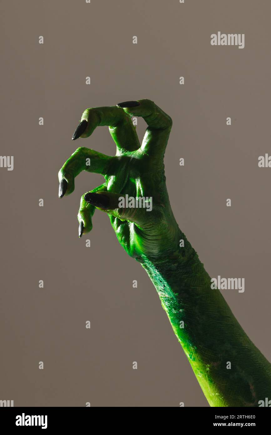 Vertical image of green monster hand with black nails making gesture on ...