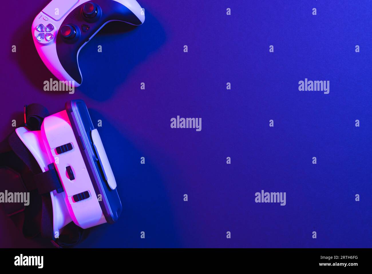 Composite of video game pad and vr headset with copy space on neon ...