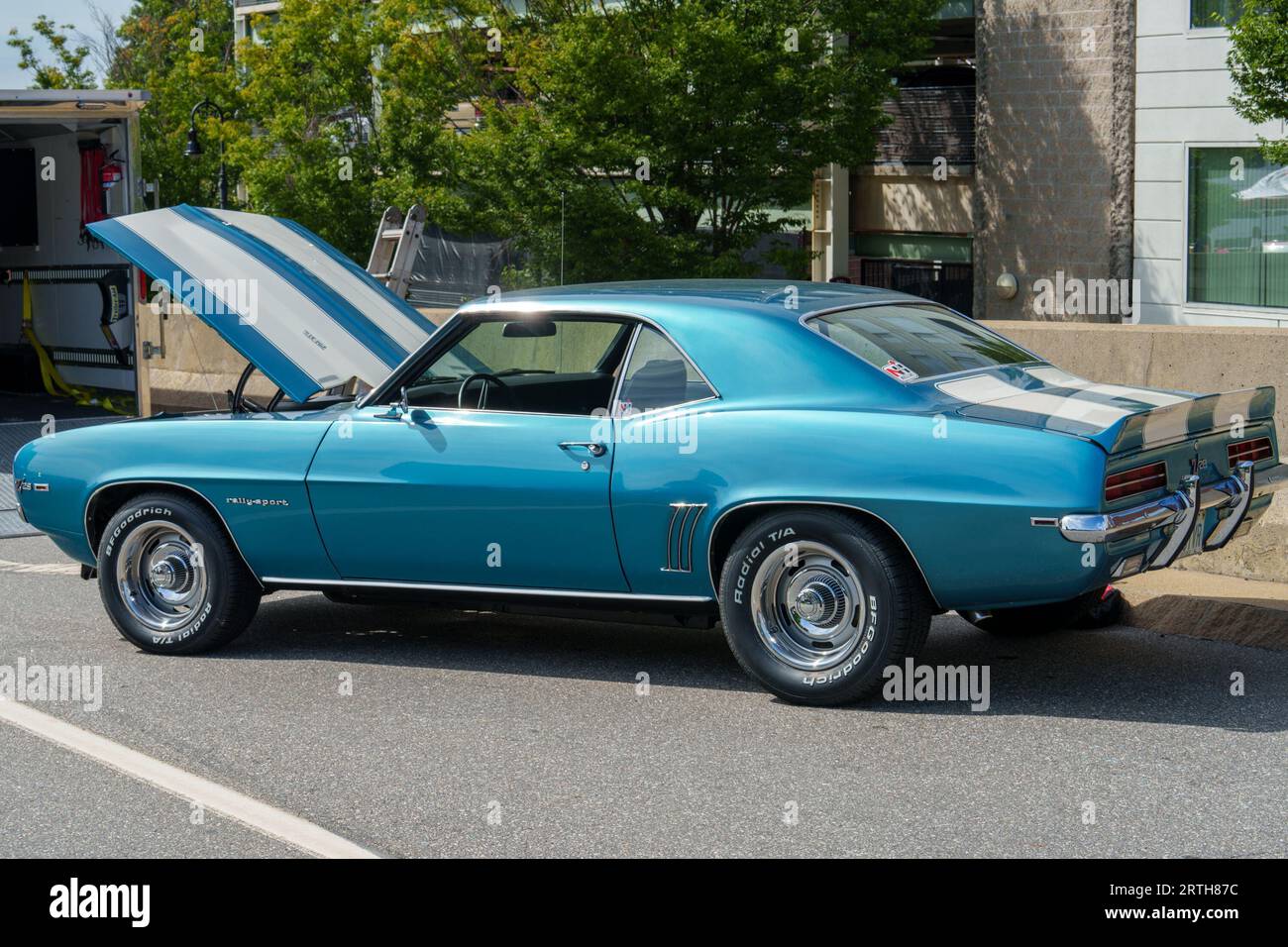 A blue and white rally sport car with the bonnet open, parked in a ...