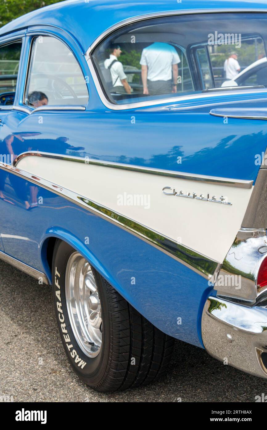A classic blue Chevrolet car with white design parked in an open lot ...