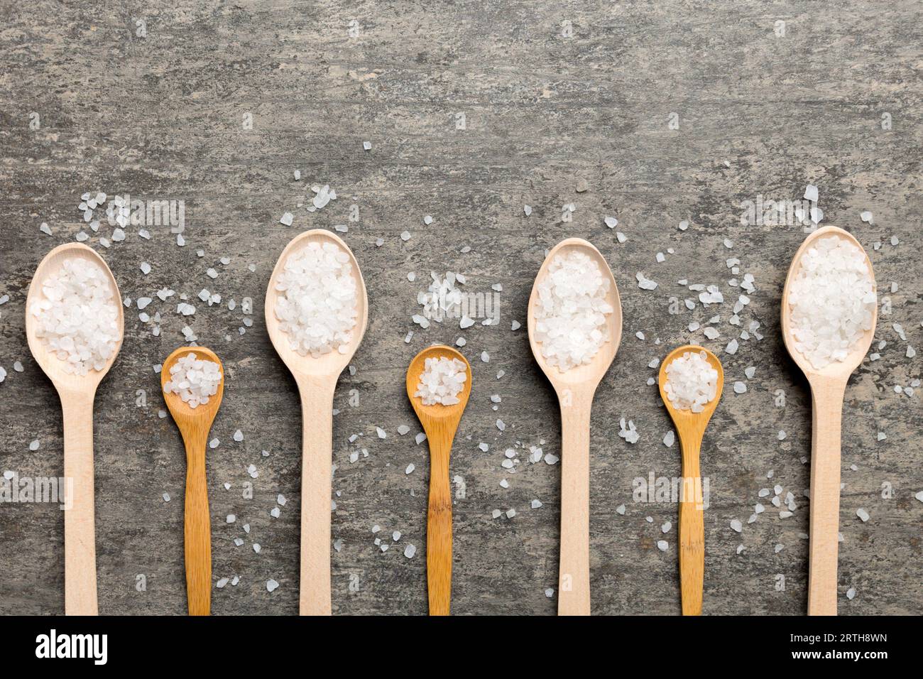 salt on many wooden spoon on wood background. Spoons with different ...