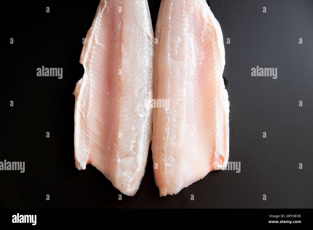 Whitefish fillets on the black background. Top view Stock Photo - Alamy