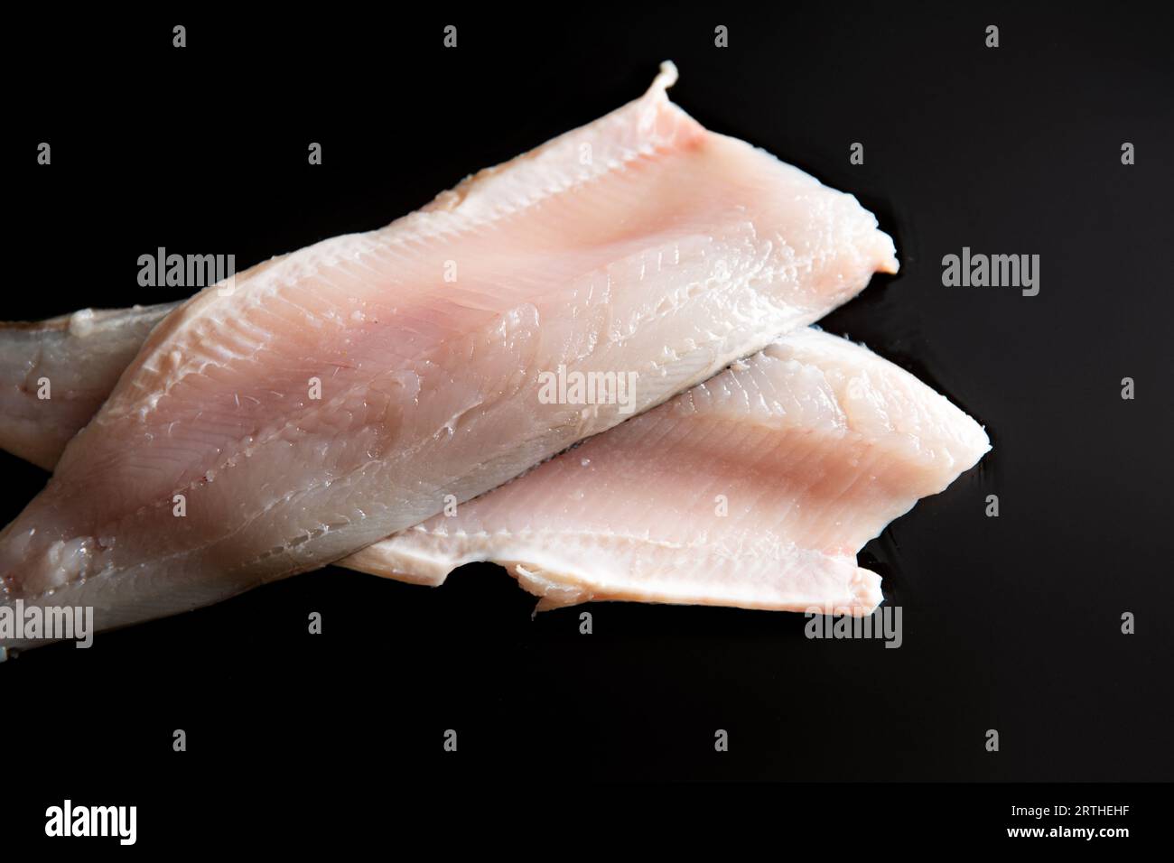 Whitefish fillets on the black background. Top view Stock Photo - Alamy