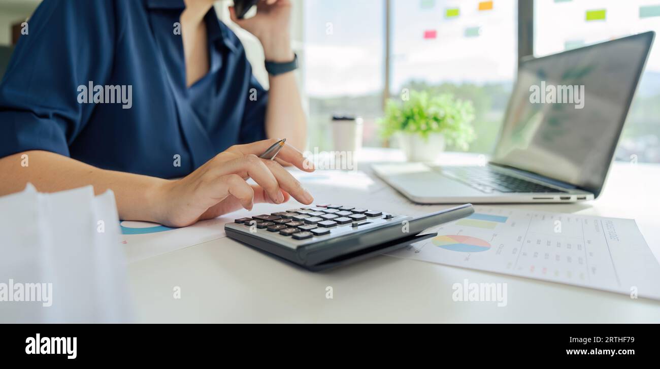 Businesswoman using a calculator to calculate numbers on a company's ...